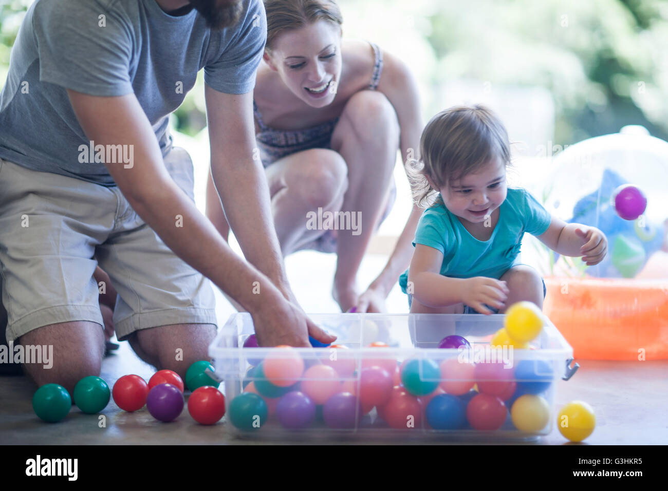 Parents and daughter playing with balls on floor Stock Photo - Alamy