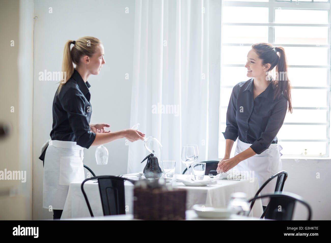 Waitresses chatting and setting table in restaurant Stock Photo - Alamy