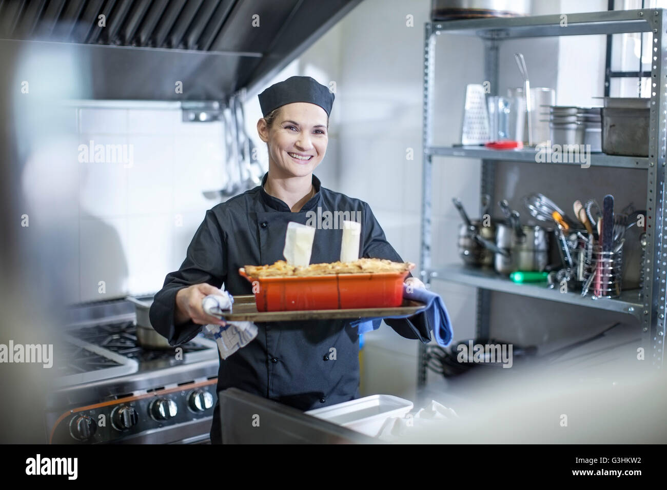 Happy chef with tray of baked food in kitchen Stock Photo - Alamy