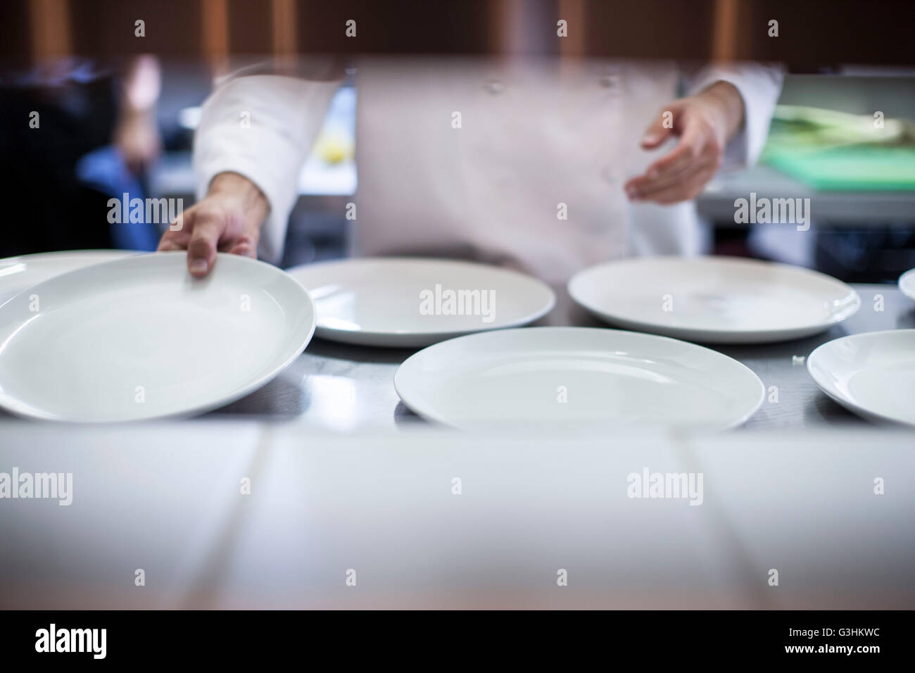 Chef laying out empty plates in kitchen Stock Photo - Alamy