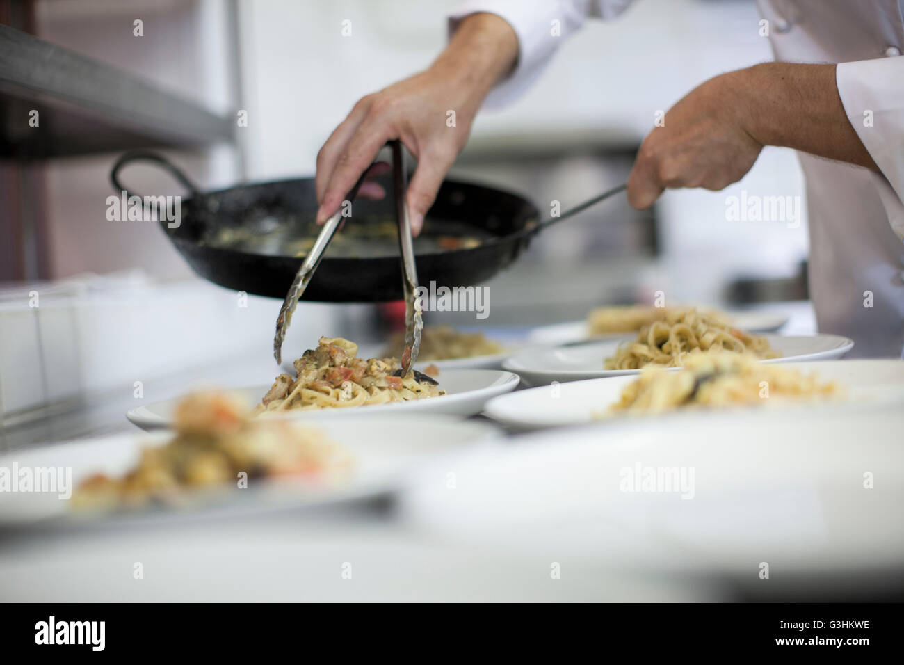 Chef filling plates with pasta in kitchen Stock Photo - Alamy
