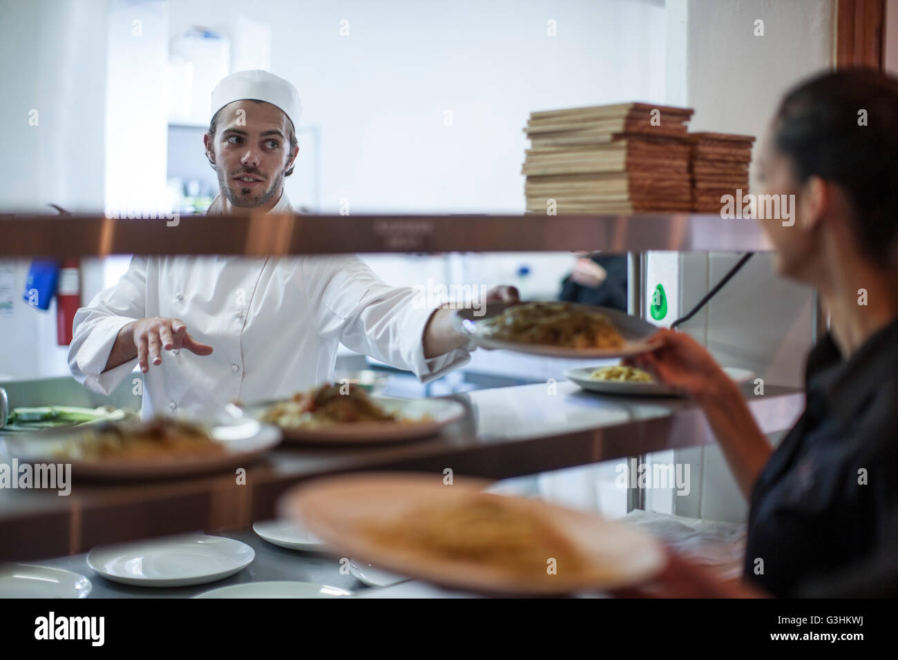 Waitress taking meal off kitchen counter for customer Stock Photo - Alamy