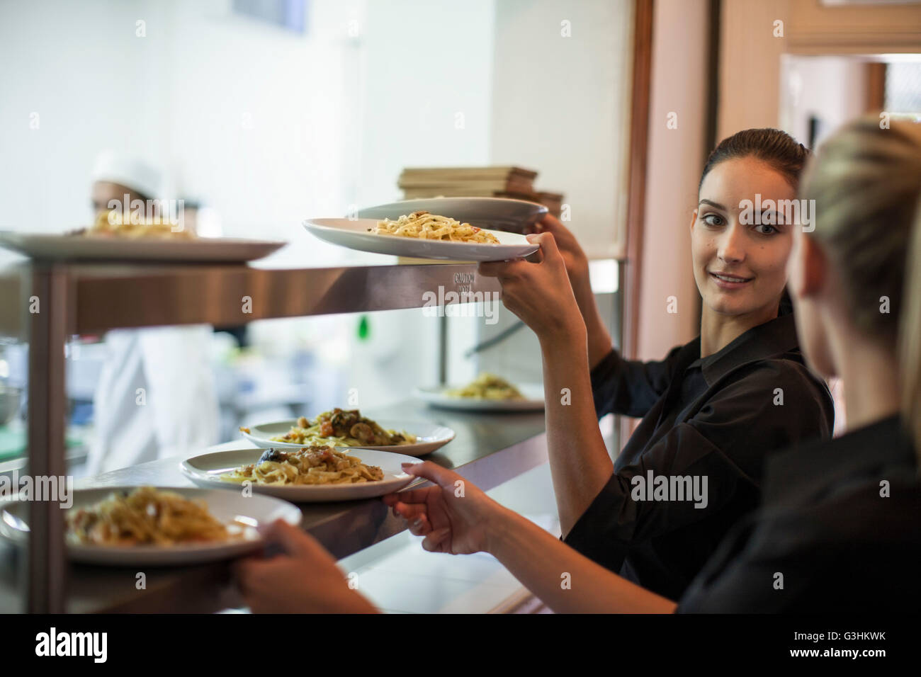 Waitress taking meal off kitchen counter for customer Stock Photo - Alamy