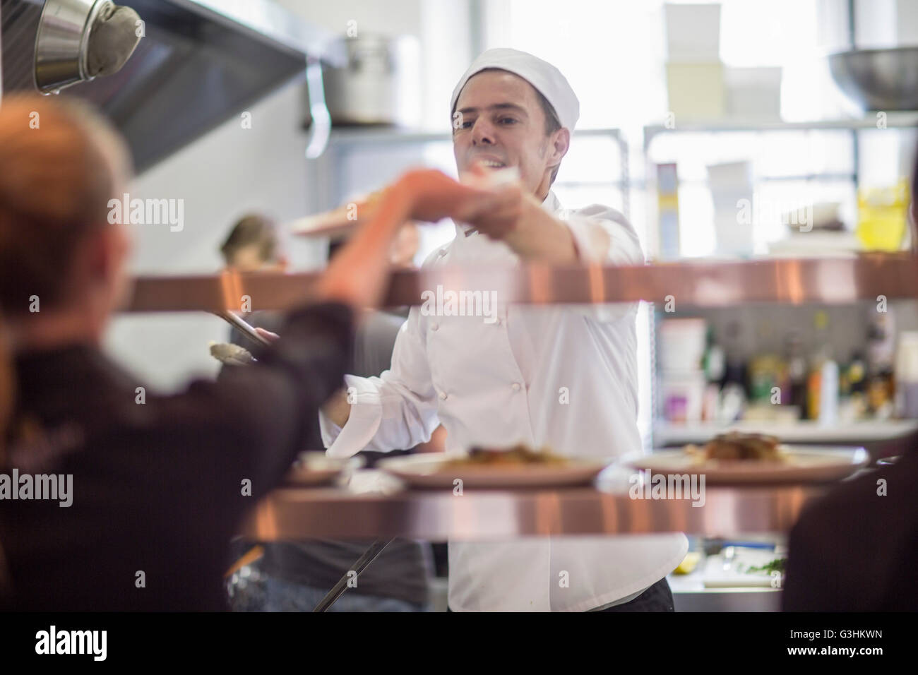 Waitress taking meal off kitchen counter for customer Stock Photo - Alamy