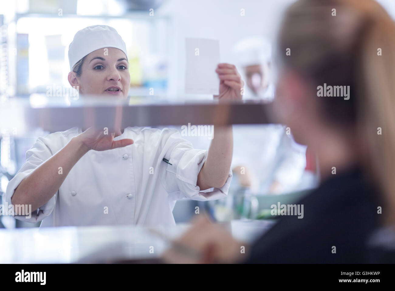 Chef taking orders from waitress in kitchen Stock Photo - Alamy