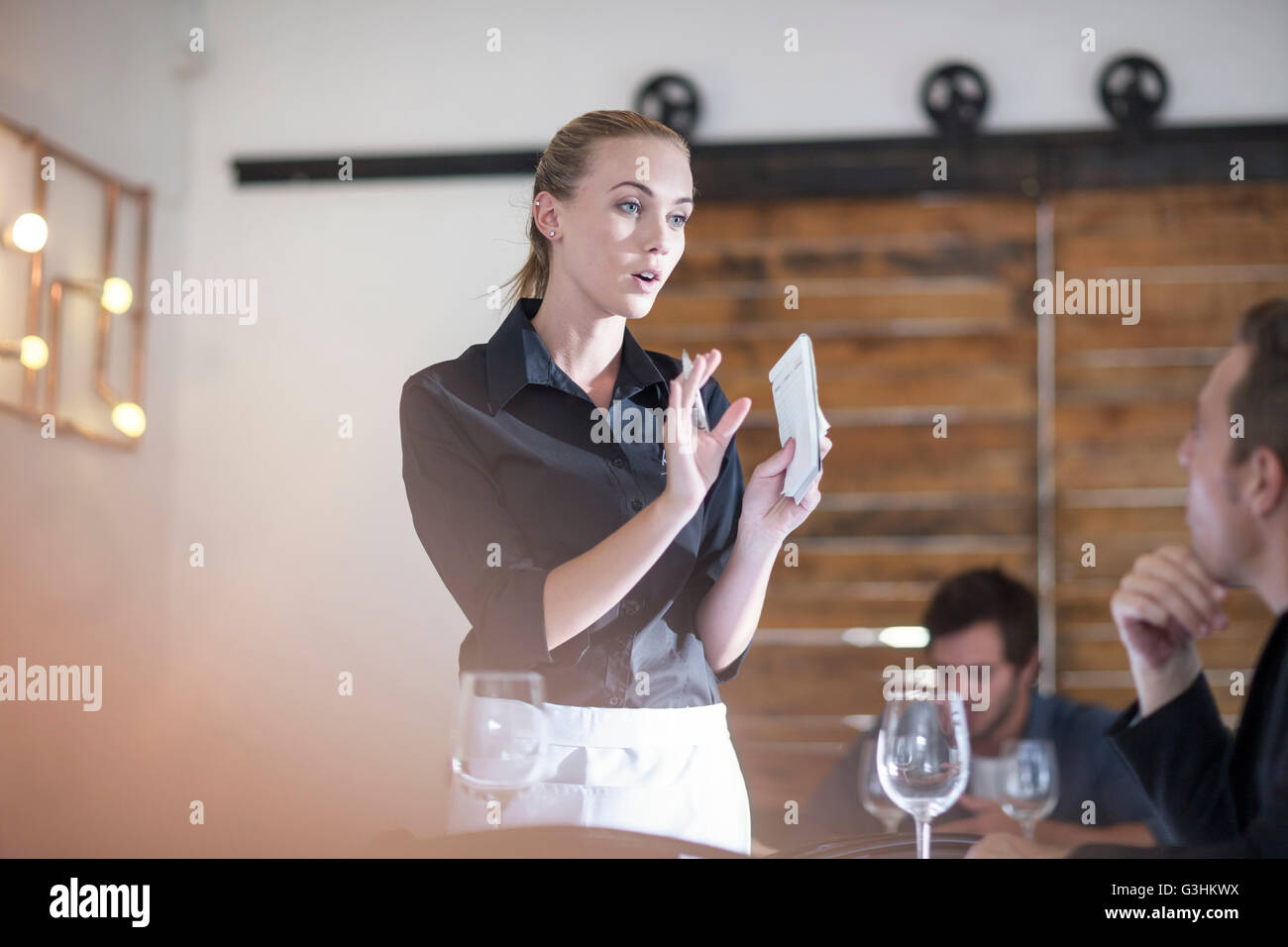Waitress explaining to customer in restaurant Stock Photo - Alamy