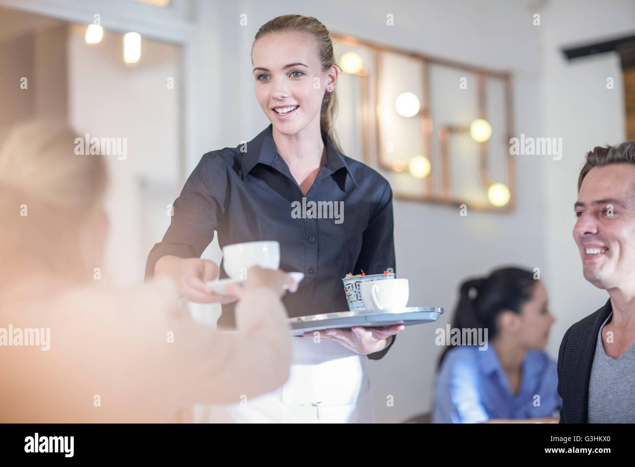Waitress serving coffee to customers in restaurant Stock Photo - Alamy