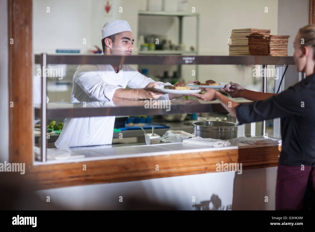Waitress taking meal off kitchen counter for customer Stock Photo - Alamy