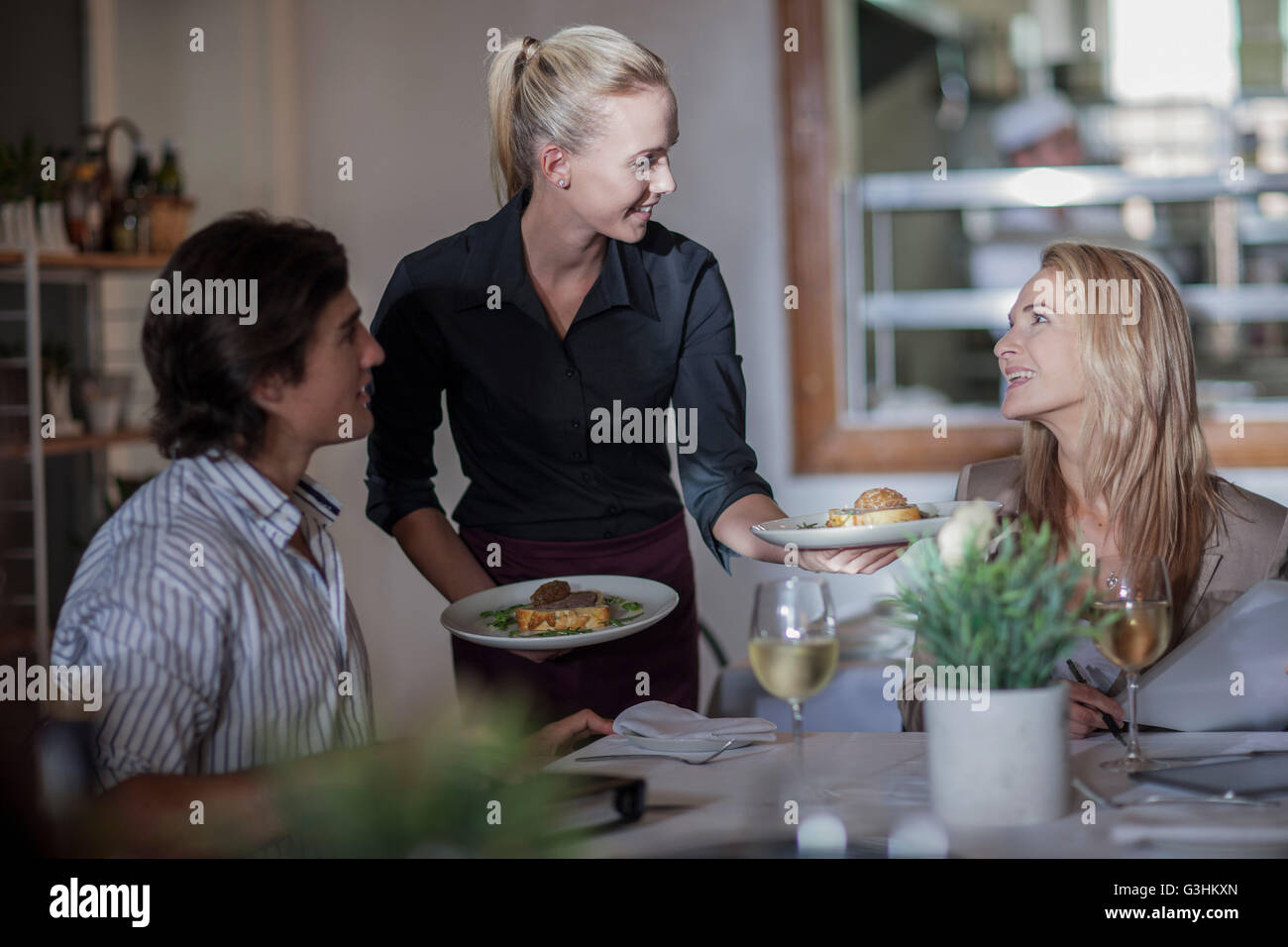 Waitress serving customers in restaurant Stock Photo - Alamy