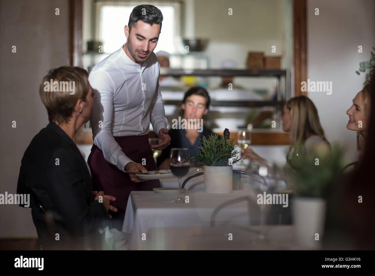 Waiter serving customer in restaurant Stock Photo - Alamy