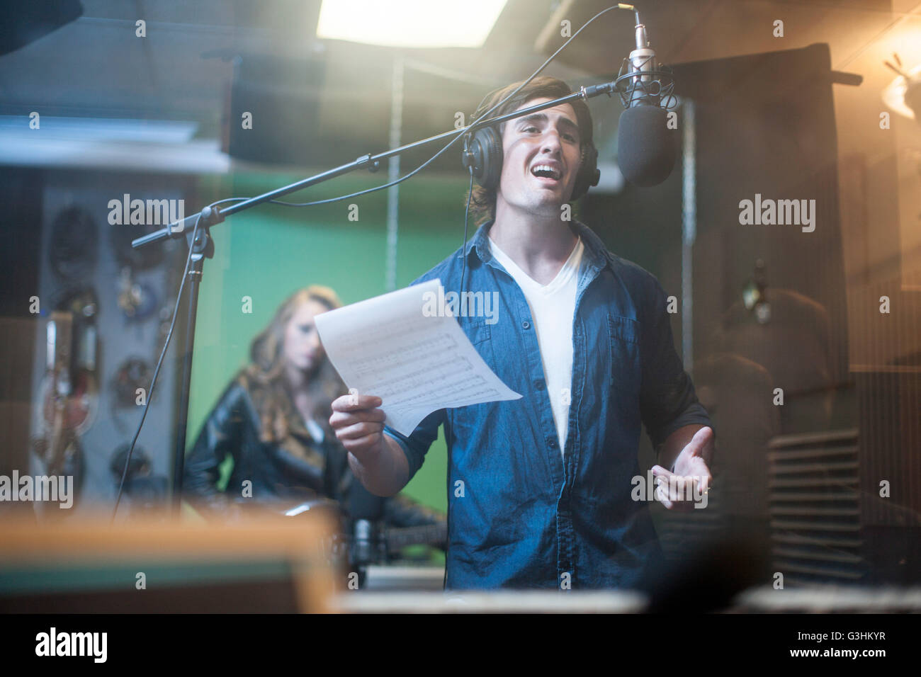 Male musician in recording studio, singing into microphone Stock Photo ...