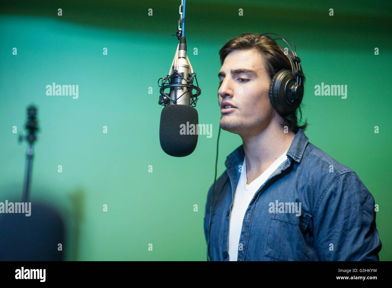 Male musician in recording studio, singing into microphone Stock Photo ...