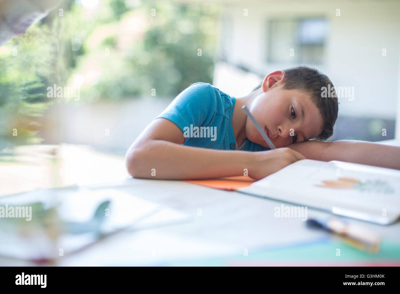 Young boy sitting at table, drawing with pencil Stock Photo - Alamy
