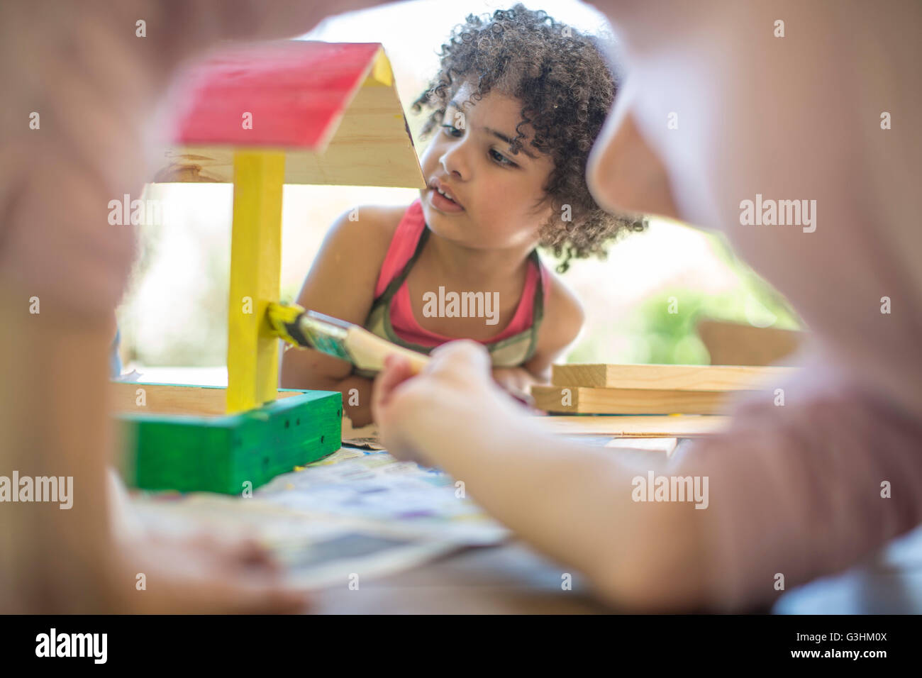 Family doing crafts together, painting wooden birdhouse Stock Photo - Alamy