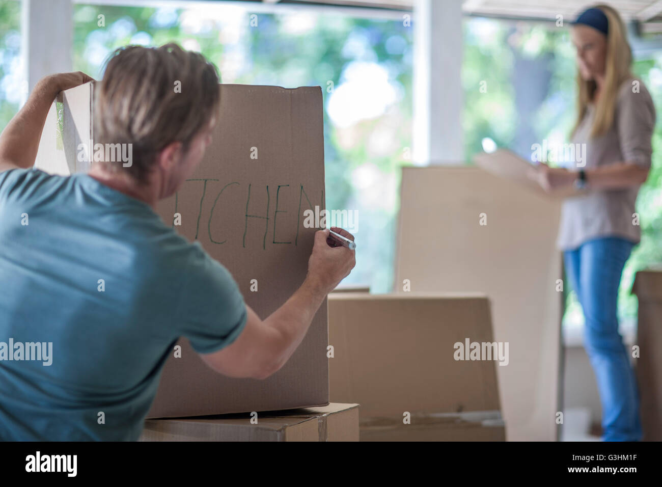 Moving house: man writing on cardboard box Stock Photo - Alamy