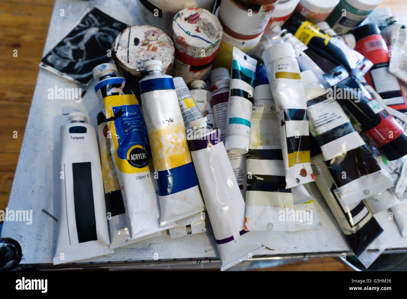 Overhead view with variety of artist paint tubes and pots on table ...