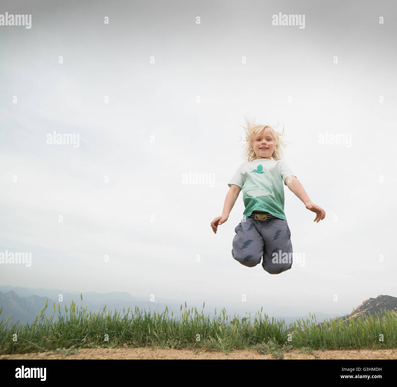 Boy jumping in mid air looking at camera smiling Stock Photo - Alamy