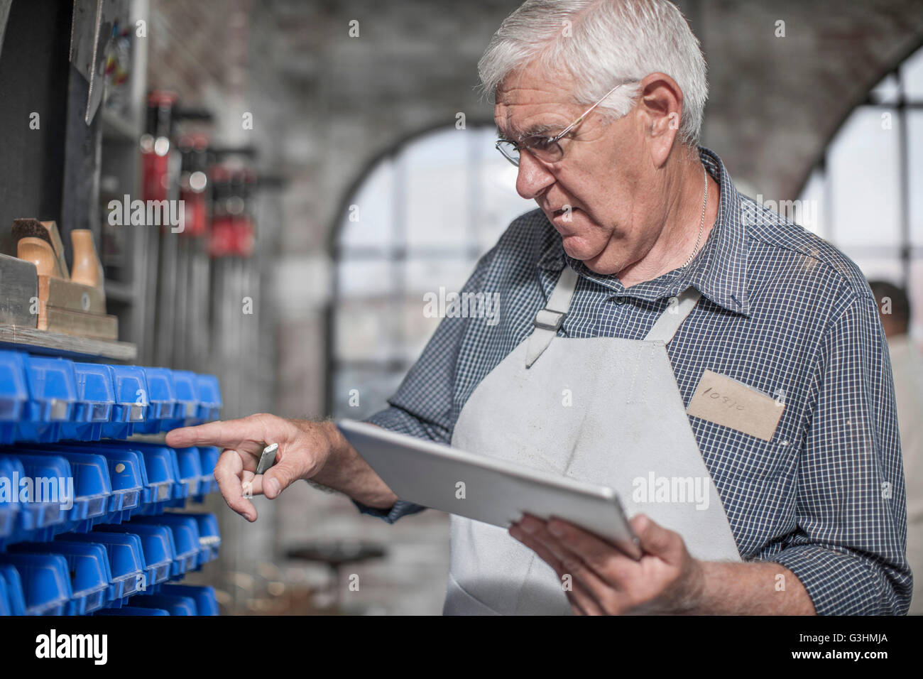 Senior craftsman with digital tablet selecting components in antique ...