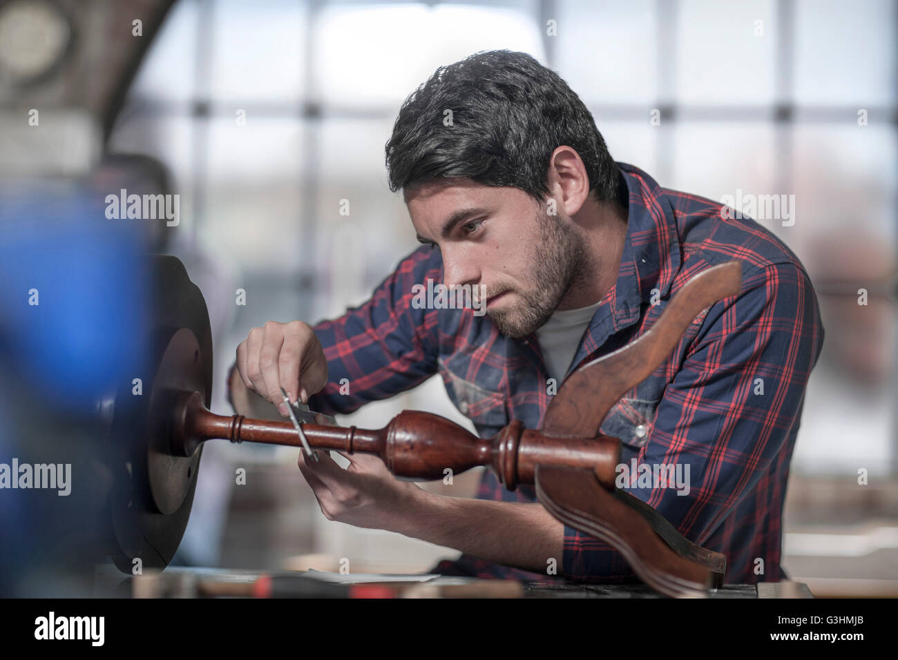 Young craftsman measuring table with gauge in antique restoration ...