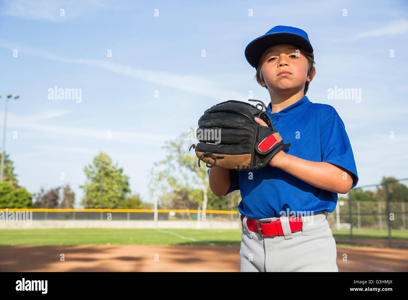 Portrait of confident boy wearing baseball glove at baseball practise ...