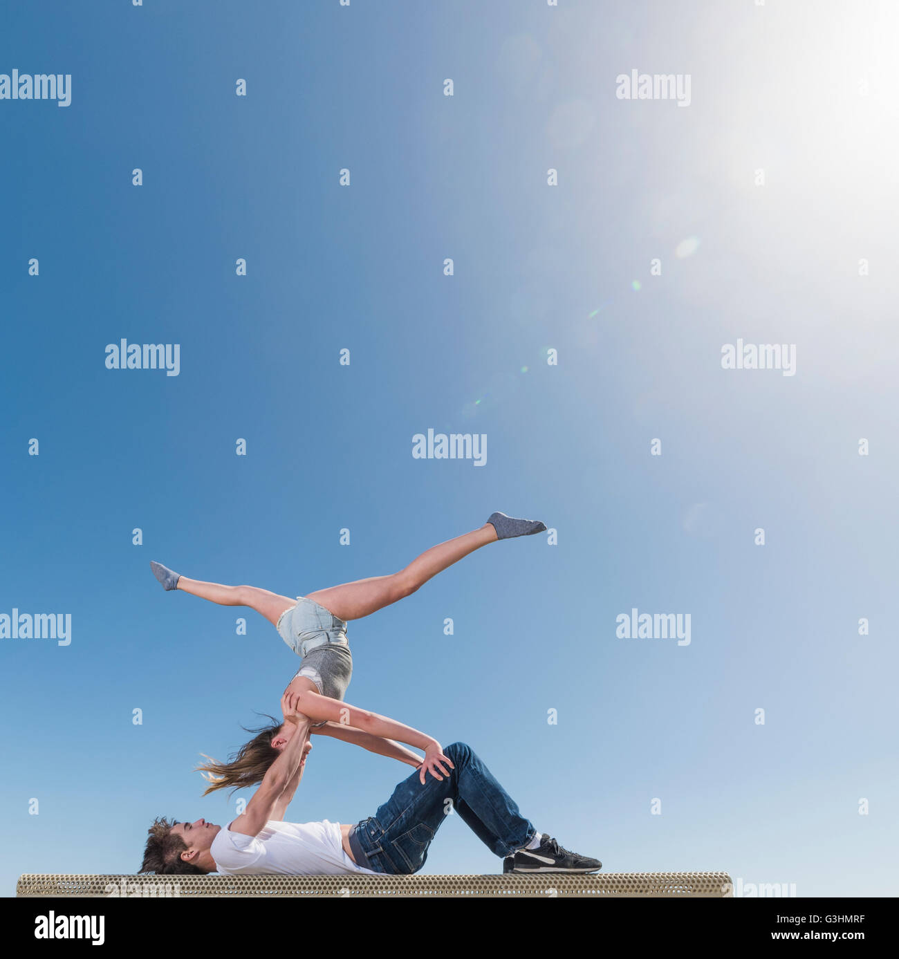 Couple practising partner yoga on bench Stock Photo - Alamy