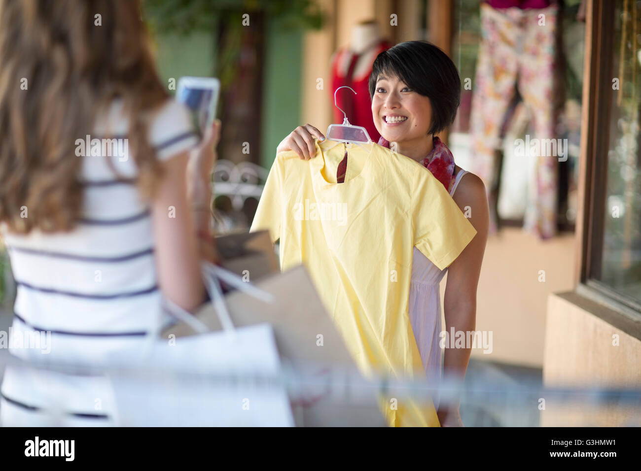 Two young women photographing dress on smartphone in city Stock Photo ...