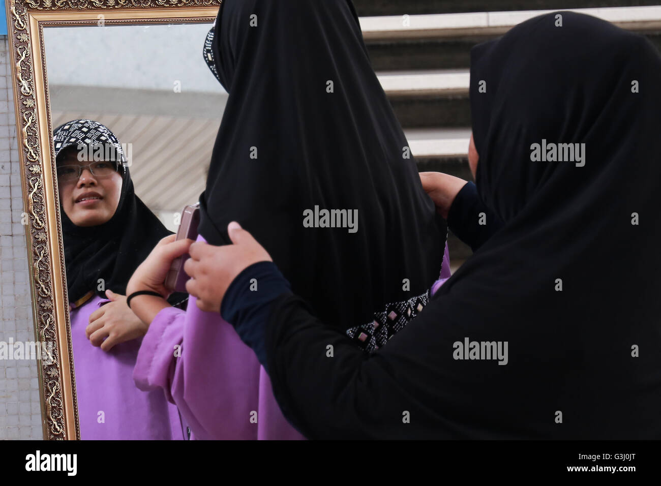 A mosque guardian sheathes veil to a non muslim visitor to cover awrah ...