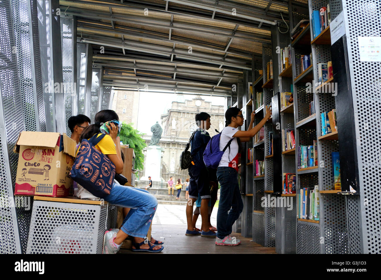 A park goers taking copy of their book on open library in front of ...