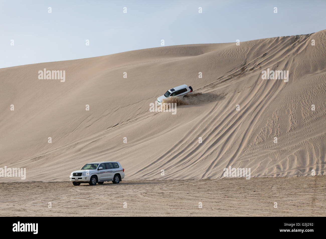 4 x 4's driving over sand dunes in the desert in Qatar. Arabian ...