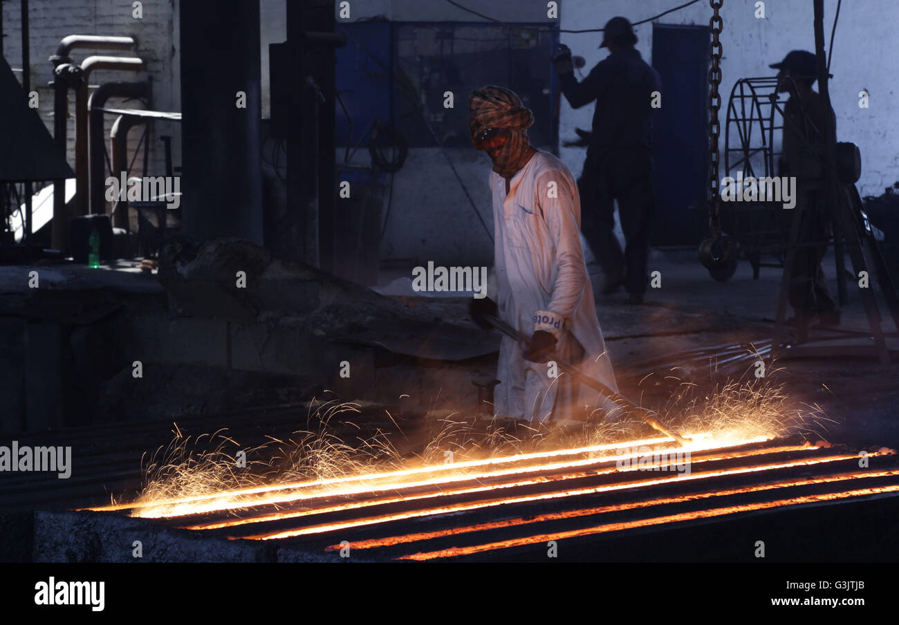 Pakistani blacksmiths work at an iron molding factory in an industrial ...
