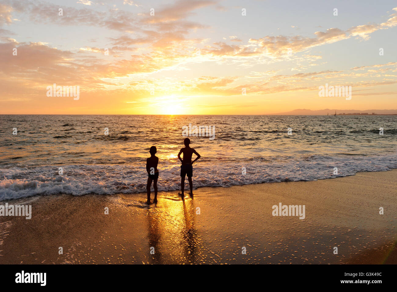 Boys beach sunset is silhouettes of two boys watching with awe as the ...