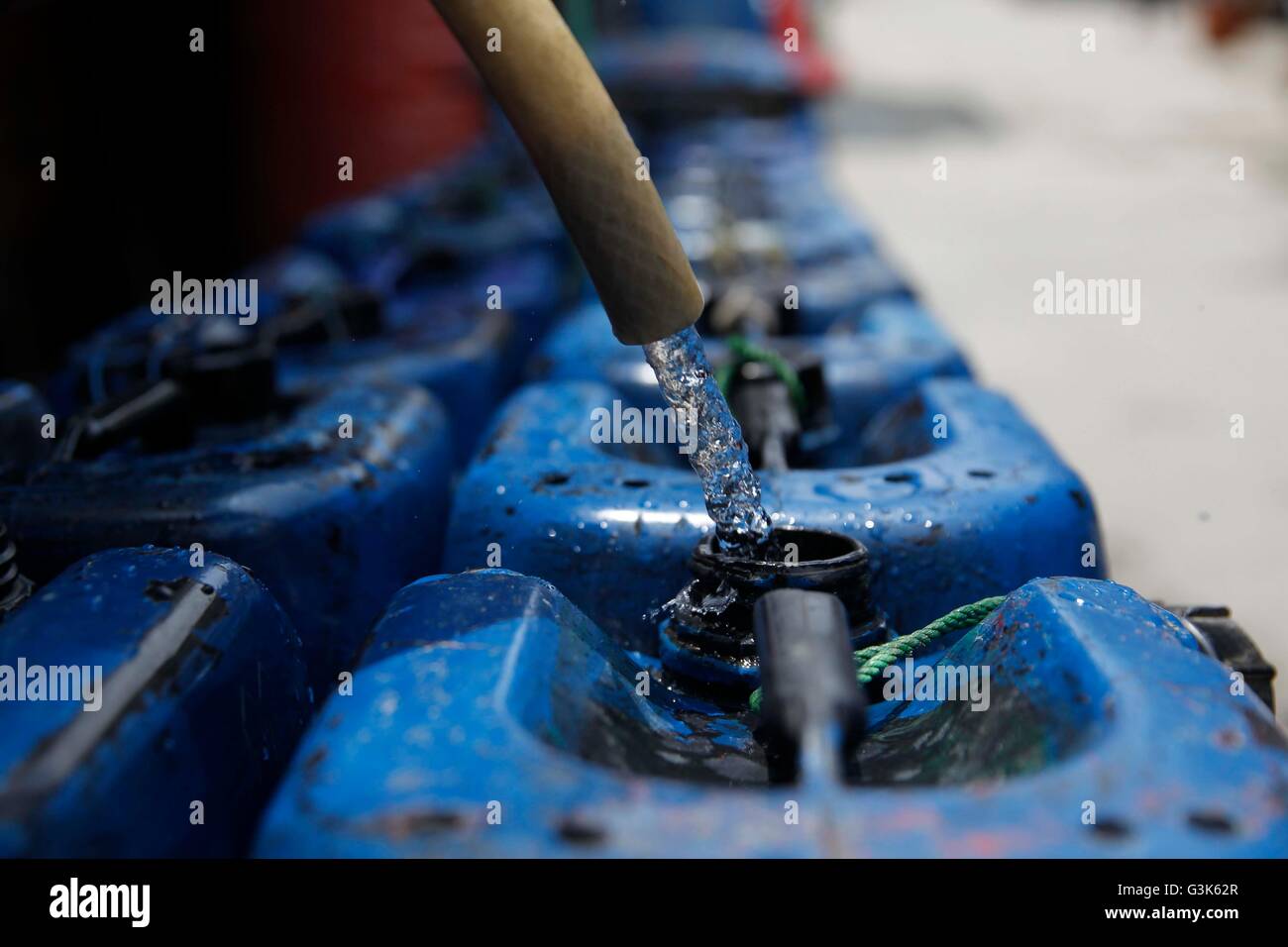 A man fill clean water into plastic containers at a pump station before ...