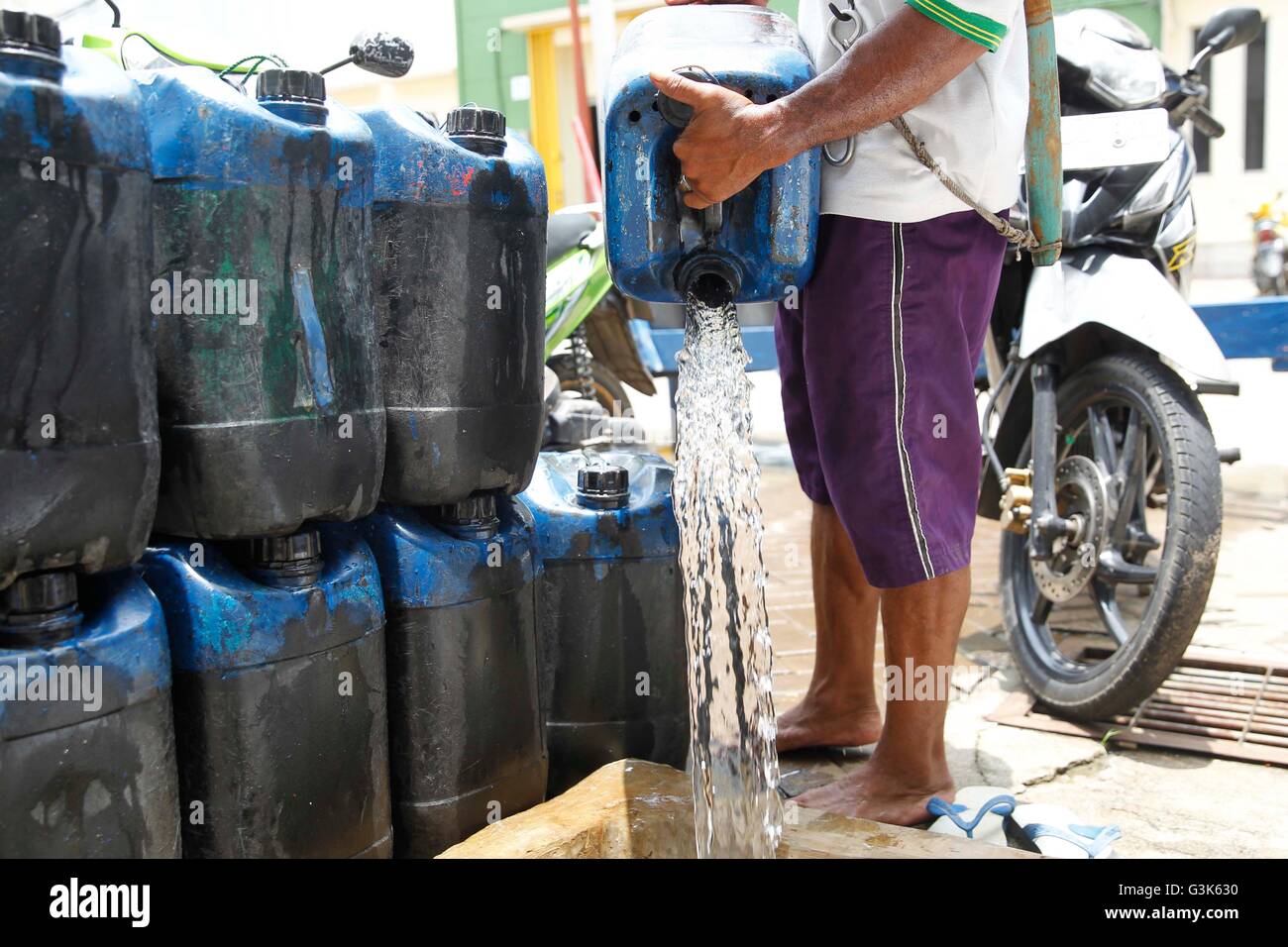 A man fill clean water into plastic containers at a pump station before ...