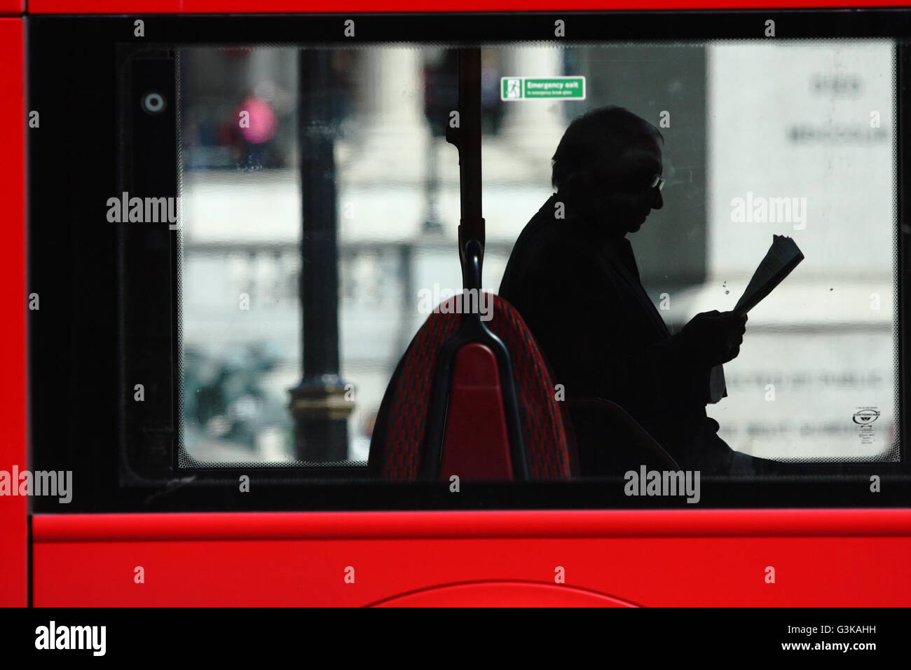 A view of a male reading a newspaper while sitting inside a red London ...