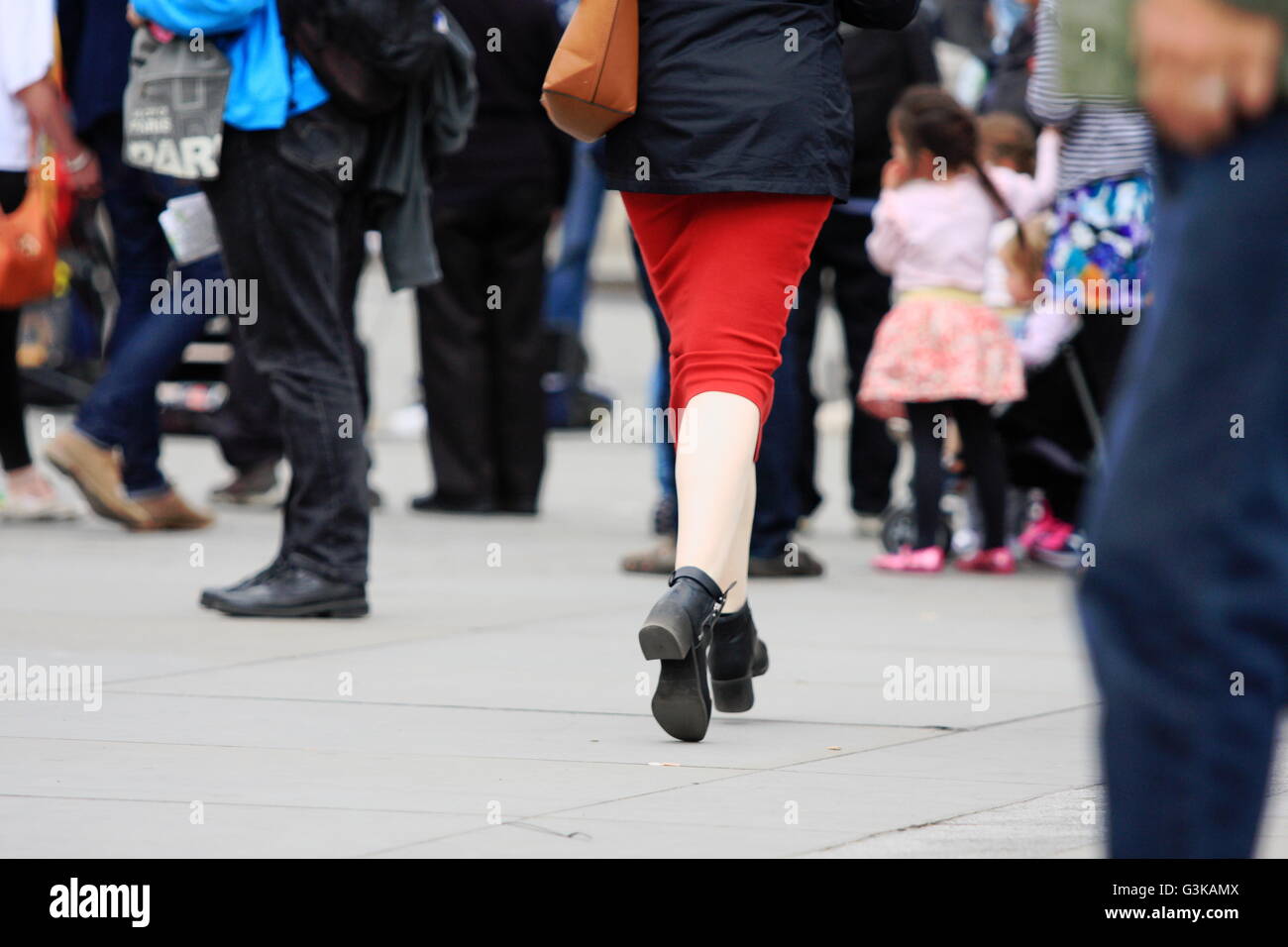 Legs of a woman walking through crowds in Trafalgar Square, London ...