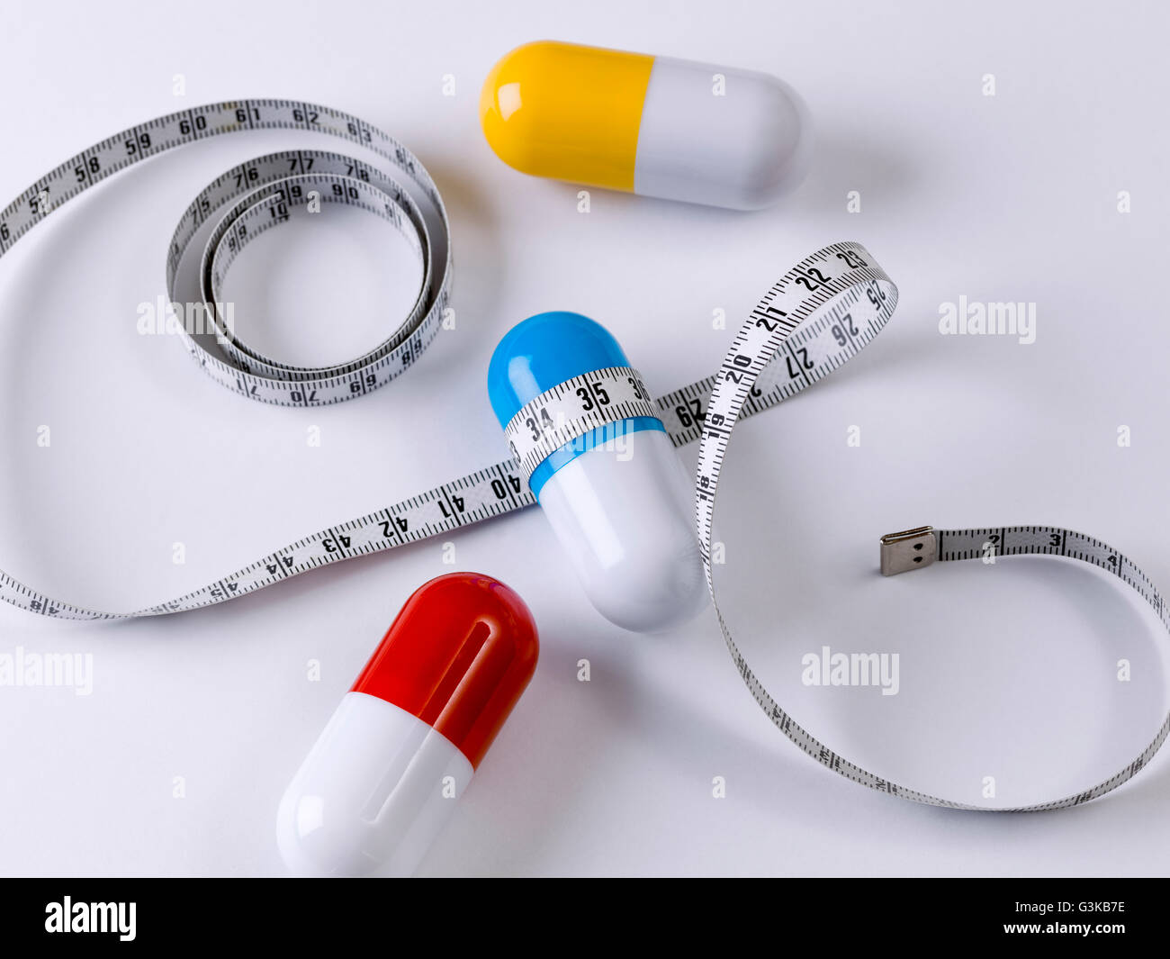 Slimming capsules, with a tape measure wrapped around one Stock Photo ...