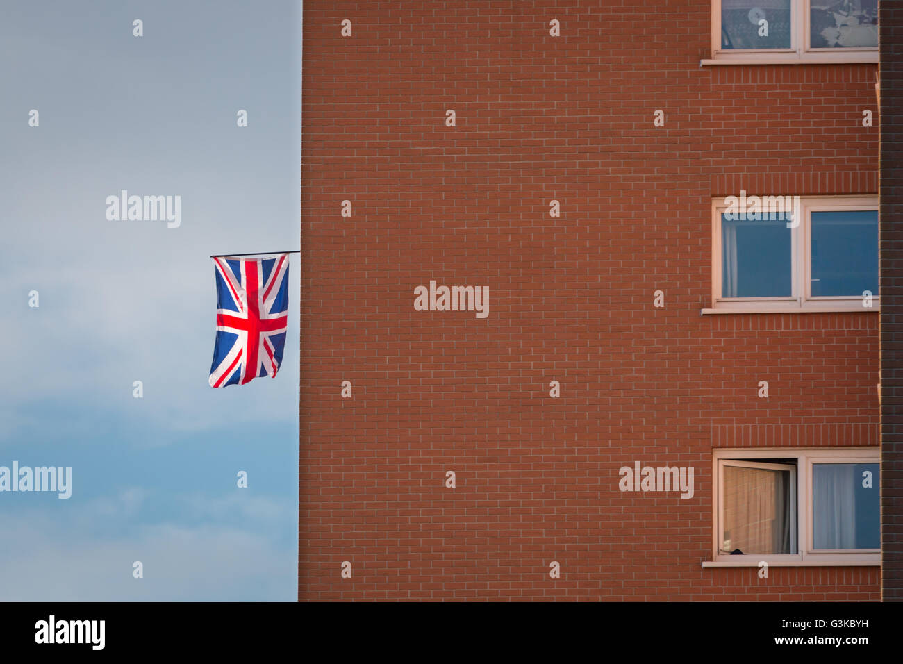 A Union Jack hanging from a window in a block of flats Stock Photo - Alamy