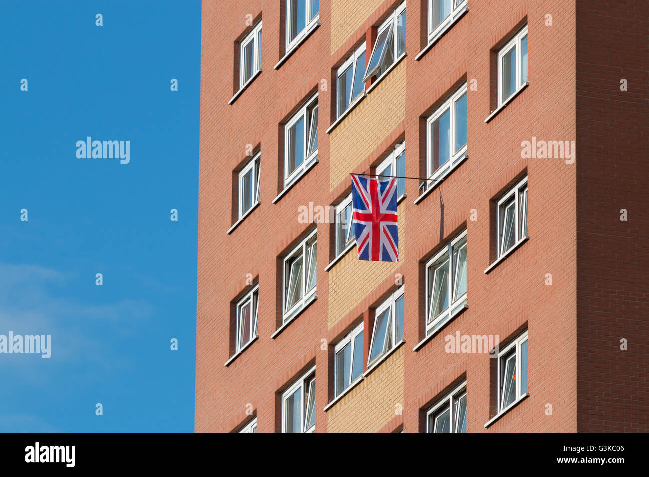 A Union Jack hanging from a window in a block of flats Stock Photo - Alamy