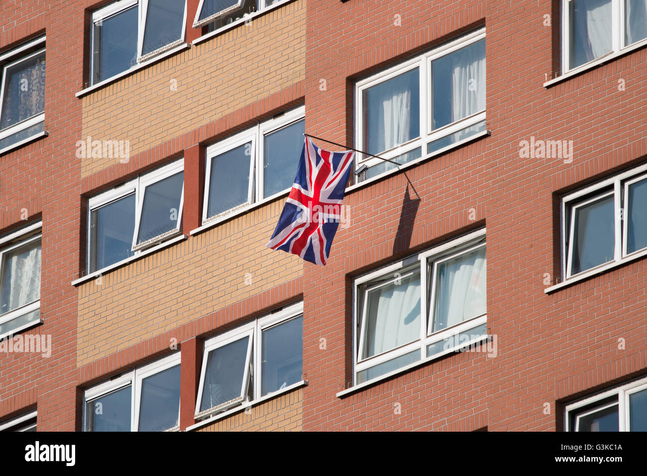 A Union Jack hanging from a window in a block of flats Stock Photo - Alamy