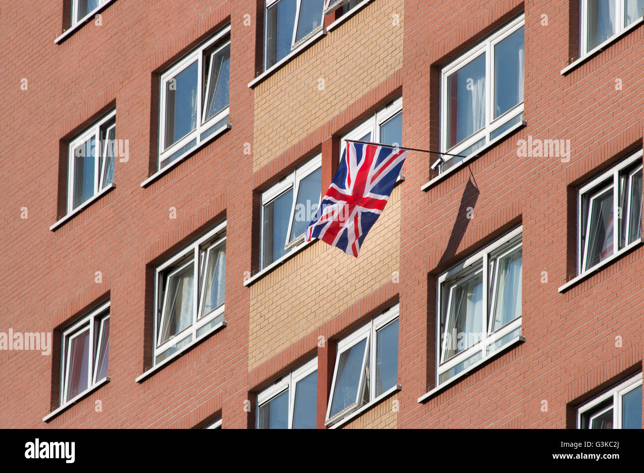 A Union Jack hanging from a window in a block of flats Stock Photo - Alamy