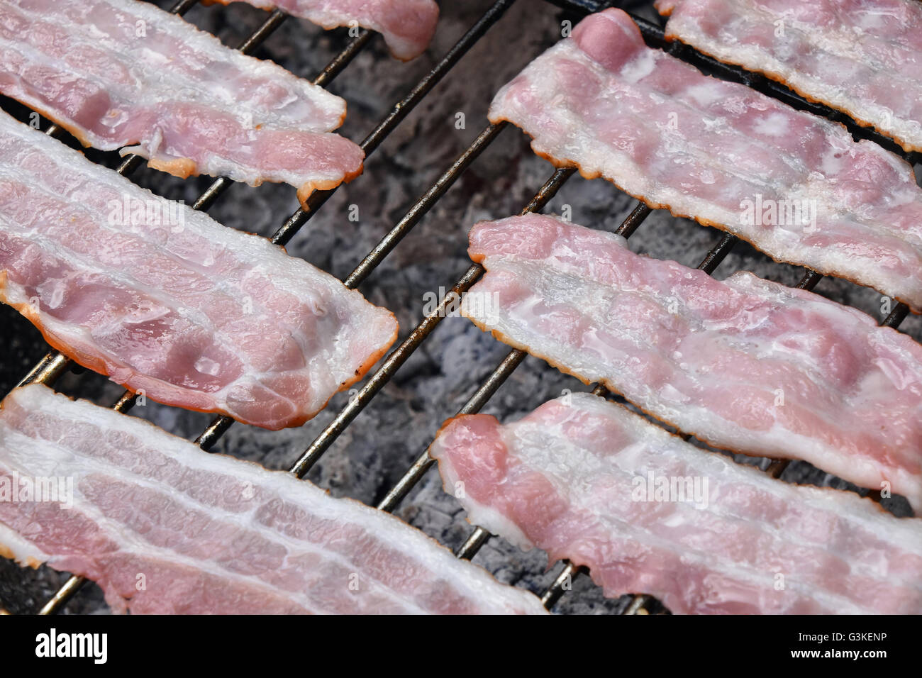 Raw smoked melting grilled barbecue bacon slices, being cooked on bbq ...