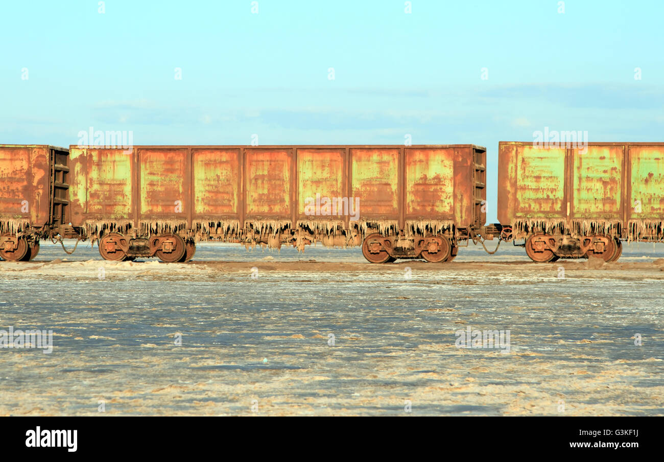 Old rusty train cars with stalactites of salt in the lake Baskunchak ...