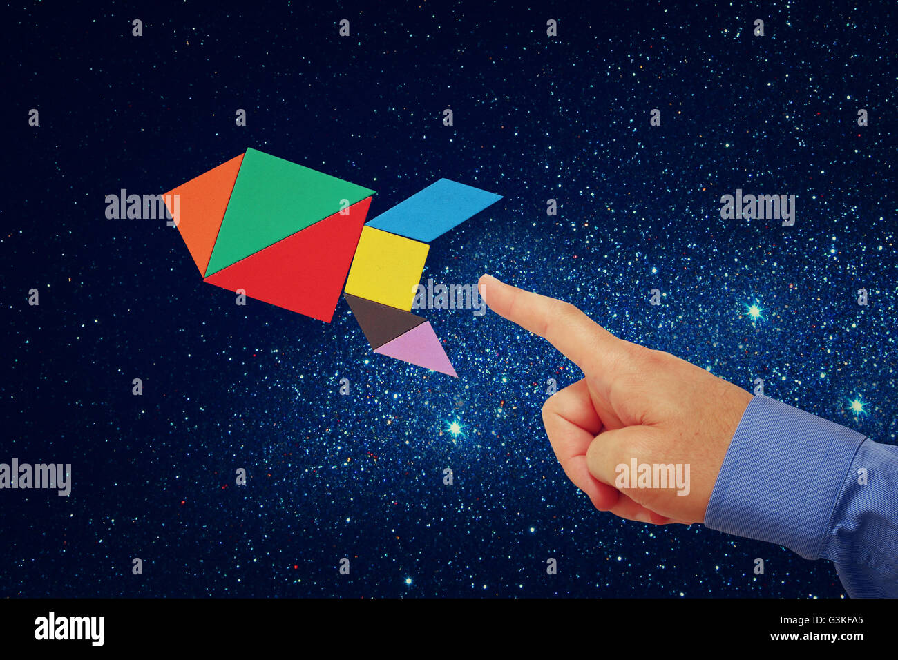 man's hand pointing at rocket made from square tangram puzzle, abstract ...