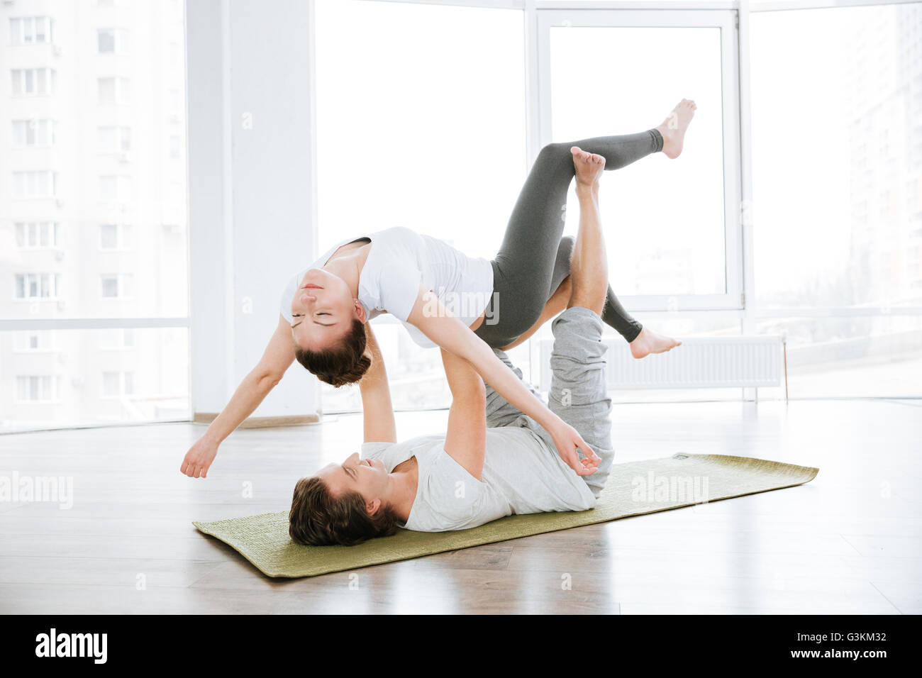 Relaxed couple practicing acro yoga exercises in studio Stock Photo - Alamy