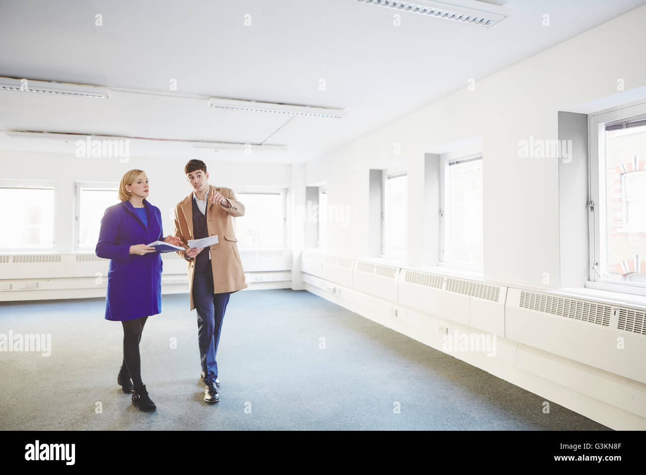 Colleagues walking through empty office Stock Photo - Alamy