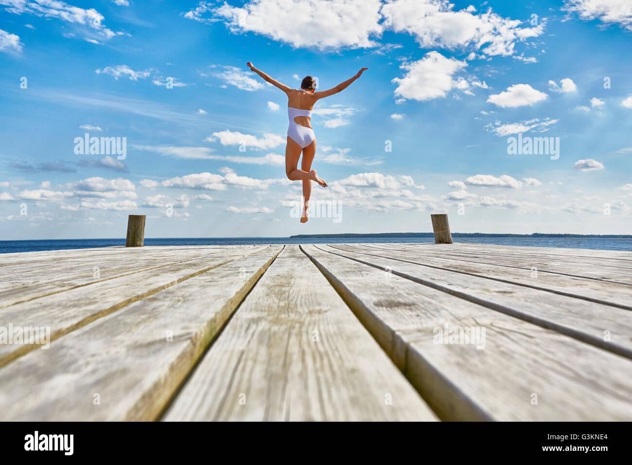Young woman dancing on wooden pier, mid air, rear view Stock Photo - Alamy