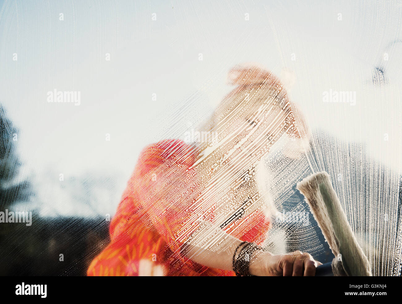 Woman outdoors cleaning soapy window with squeegee Stock Photo - Alamy