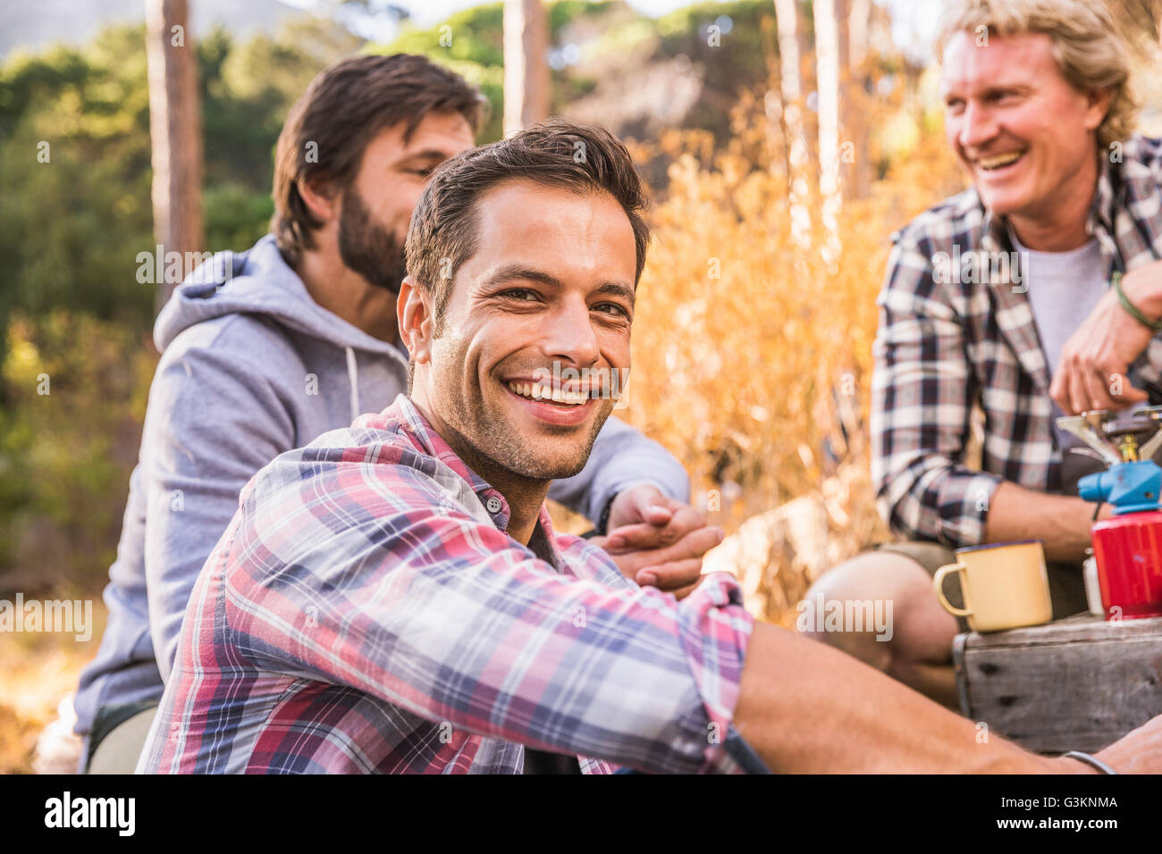 Three men cooking on camping stove in forest, Deer Park, Cape Town ...