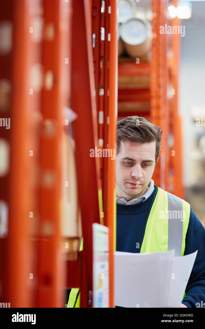 Male factory worker checking paperwork in factory warehouse Stock Photo ...
