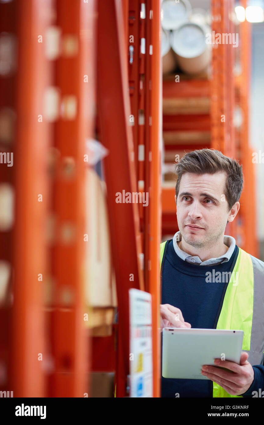 Male factory worker using digital tablet in factory warehouse Stock ...